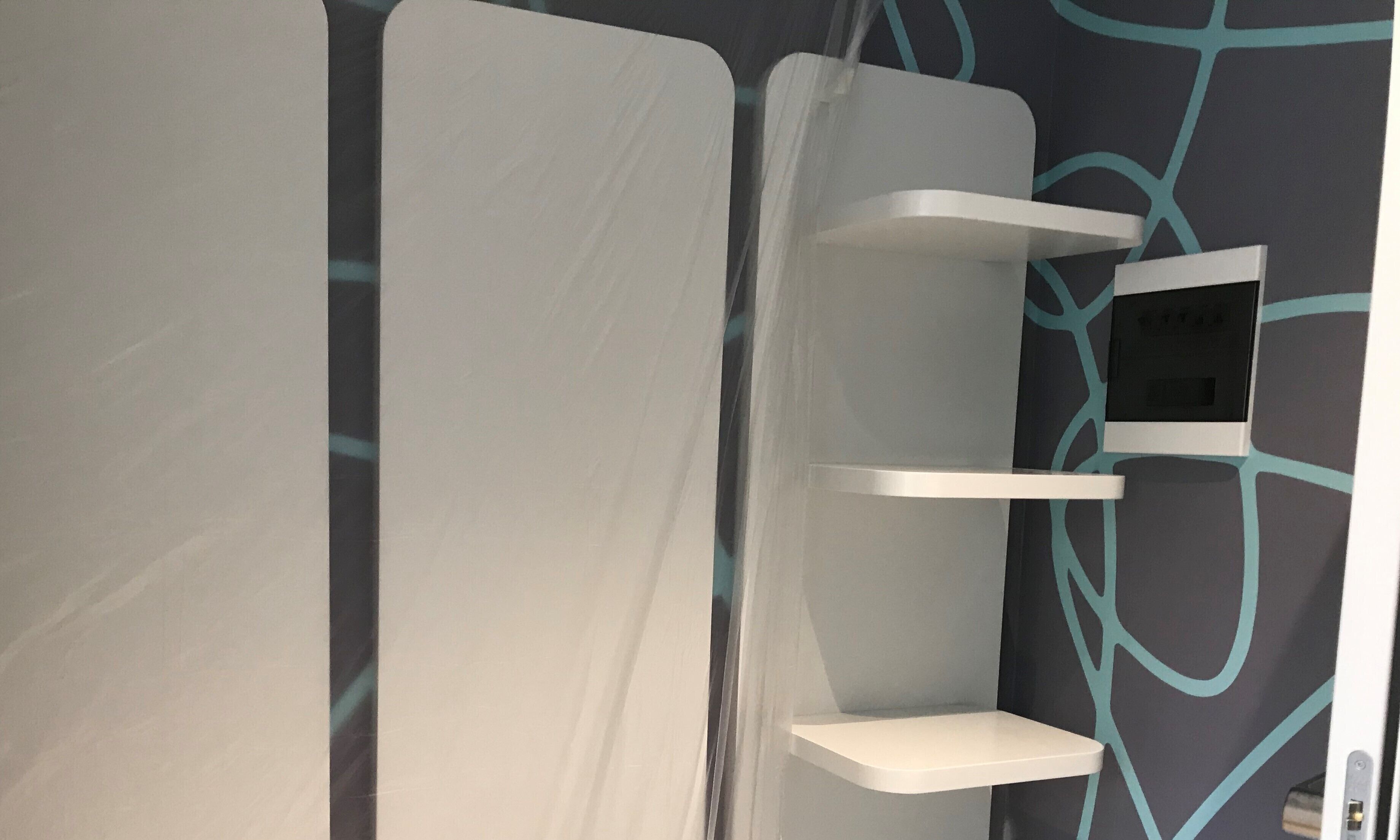 Quarto moderno com um armário branco grande e uma estante suspensa na parede com uma tela pequena.