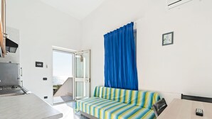 Quarto com sofá, mesa e vista através de uma porta de vidro.