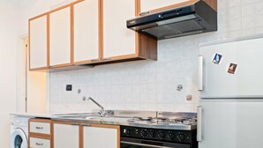 Uma cozinha compacta com armários de madeira, forno embutido, máquina de lavar e geladeira.