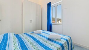 Quarto com cama, guarda-roupa, janela com cortinas e vista para o exterior.