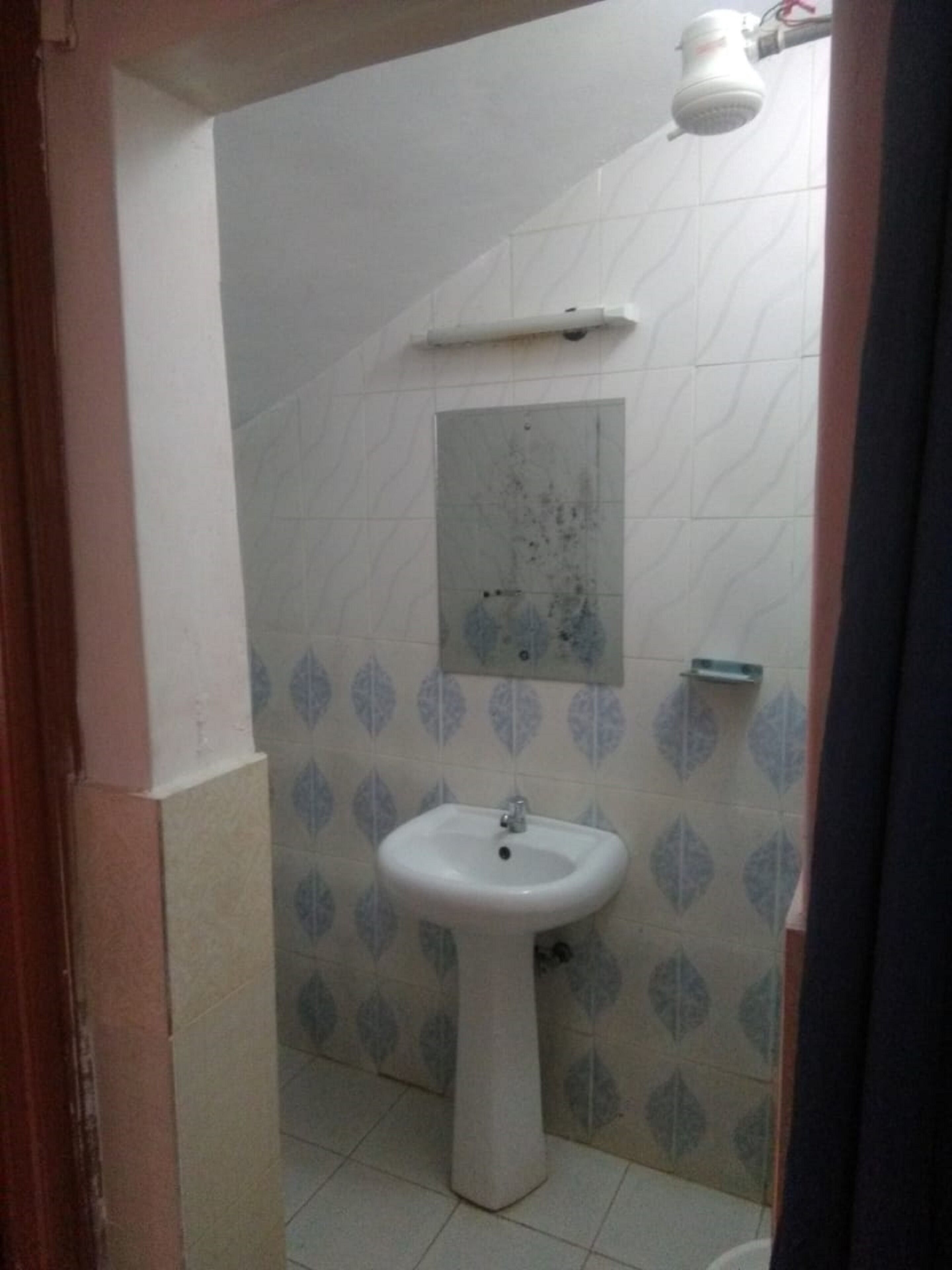 Uma casa de banho pequena com lavatório de apoio, espelho e chuveiro.