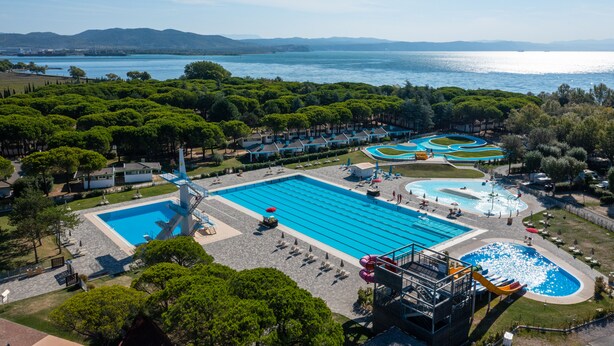 Vista aérea de um resort com uma piscina grande, um tobogã e vista para o mar.