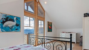 Quarto com cama, penteadeira e pintura de um pássaro.