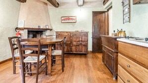 Cozinha rústica com móveis de madeira, lareira de tijolos e teto de madeira.