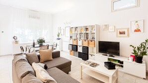 Uma sala de estar moderna com um sofá, mesa de centro, televisão e uma estante.
