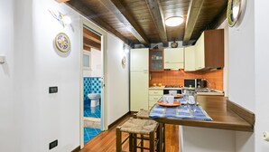Uma cozinha compacta com vigas de madeira, painel de azulejos e um pequeno espaço de refeições com banquetas.
