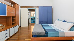 Quarto com cama, guarda-roupa de madeira e escrivaninha com gavetas.