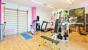Uma academia com equipamentos de exercícios, esteira e um tapete azul.