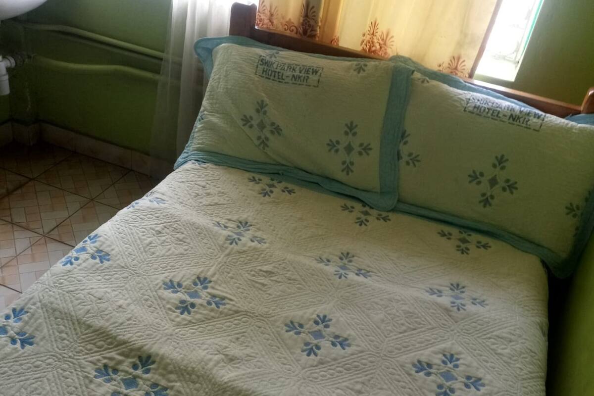 Uma cama com um edredom estampado com motivos florais e uma almofada com o nome de um hotel.
