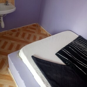 Um quarto com uma cama, uma pia branca e um chão estampado.