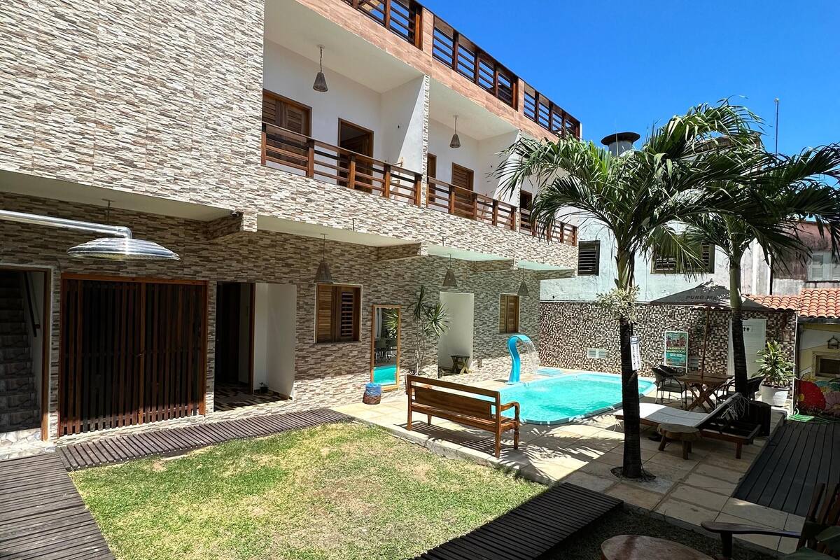 Um edifício de dois andares com fachada de pedra, piscina, área de estar ao ar livre e deck de madeira.