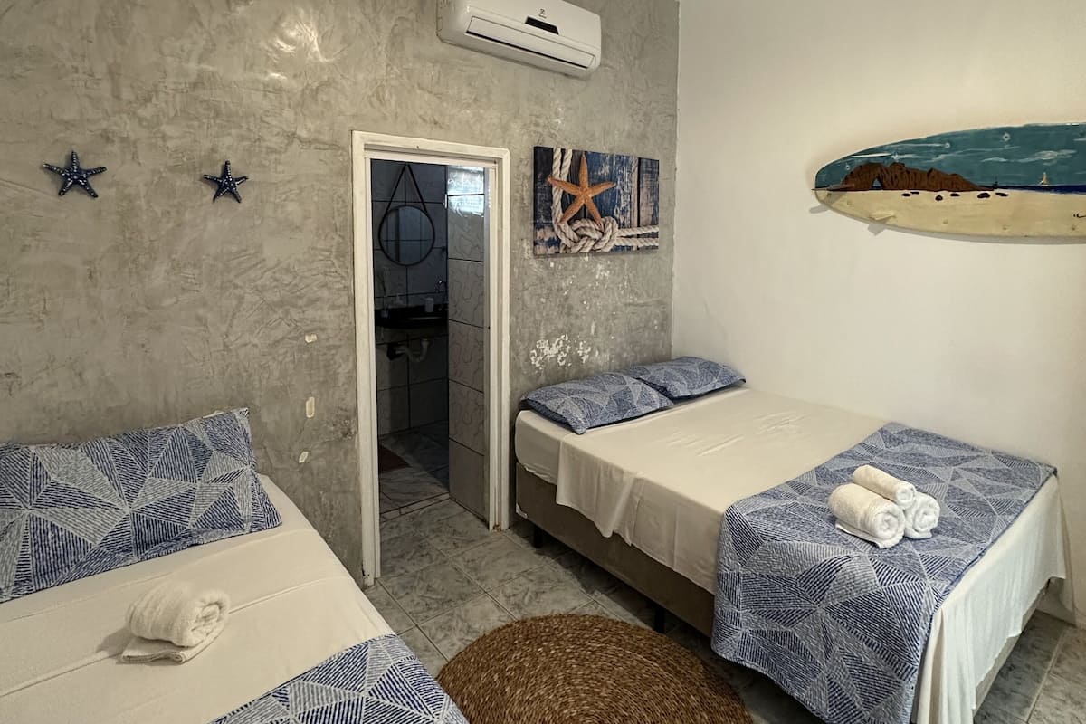 Quarto com duas camas, um tapete tecido e uma pintura de um barco na parede.