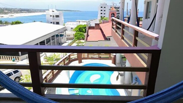 Varanda com vista para uma piscina e o mar.