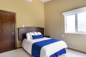 Quarto com cama, porta de madeira e janela.