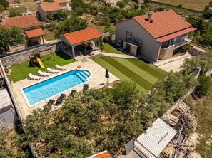 Um imóvel residencial com piscina, varanda coberta e gramado bem cuidado.
