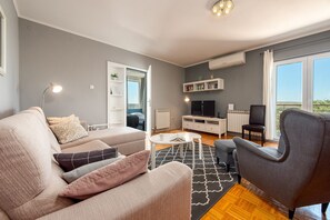 Uma sala de estar moderna com sofá, poltrona, mesa de centro e televisão.