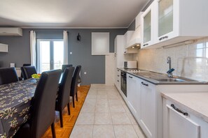 Uma cozinha moderna com armários brancos, uma pia de aço inoxidável e um espaço de jantar com mesa e cadeiras.