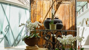 Uma porta de madeira com vasos decorativos e uma mesa de metal com orquídeas em vasos.