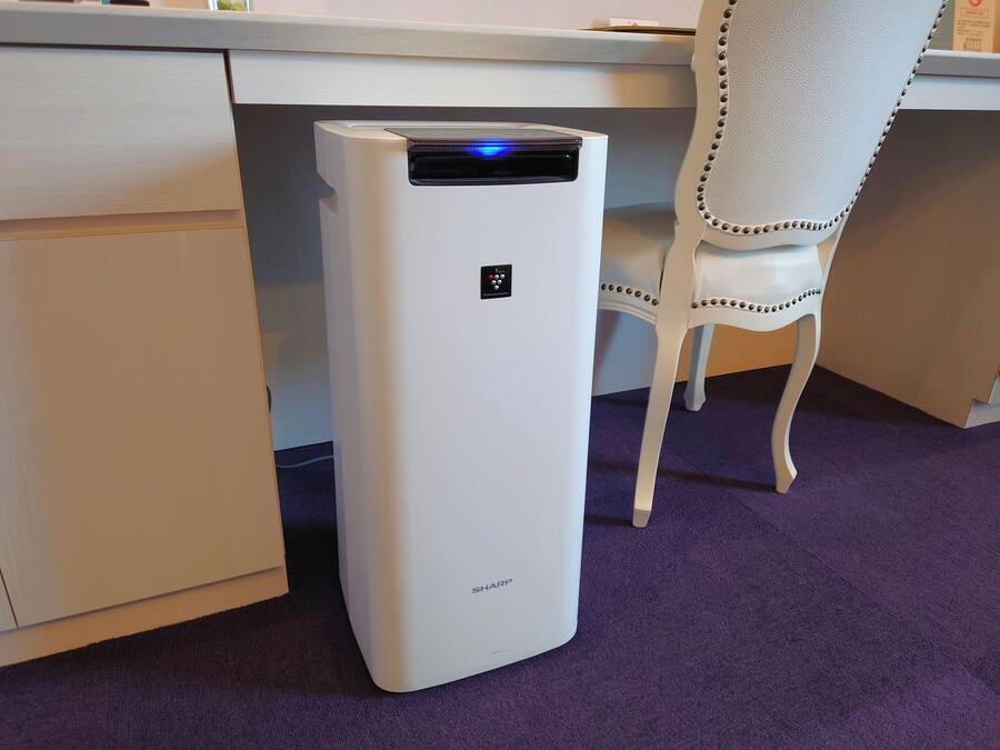 Um purificador de ar branco com visor digital e painel de controle sobre uma mesa.