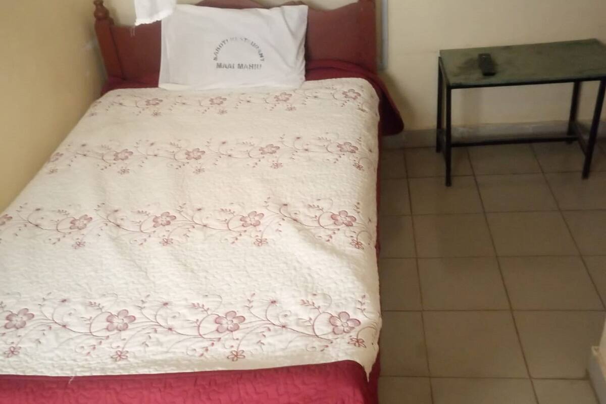 Uma cama com colcha floral, um travesseiro com texto e uma mesinha ao lado.