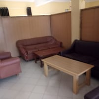 Uma sala de estar com um sofá marrom, um sofá rosa menor e uma mesa de centro de madeira.