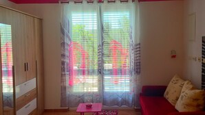 Um quarto com uma cama, um sofá vermelho, uma mesinha e um guarda-roupa.