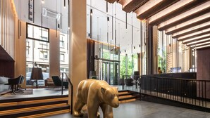 Um lobby moderno com uma grande escultura de urso, escadas e áreas de estar.