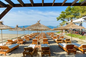 Praia particular, areia preta, espreguiçadeiras, guarda-sóis 