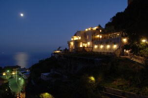 Um edifício costeiro com várias varandas e fachada de pedra, com vista para o mar.
