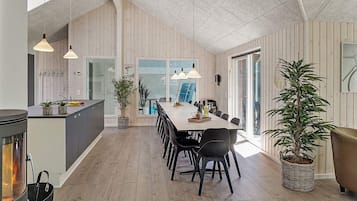 Cozinha ampla com ilha grande, piso de madeira e área de jantar com mesa e cadeiras.