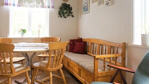 Um quarto aconchegante com um banco de madeira, uma mesa de jantar com cadeiras e uma janela com cortinas.