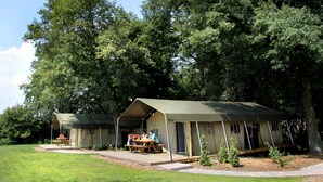 Um local de camping com duas tendas, mesas de piquenique e uma área gramada.