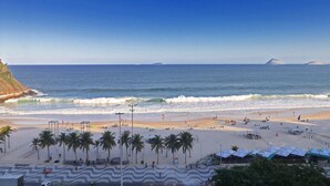 Uma praia com palmeiras, areal arenoso e céu azul límpido.