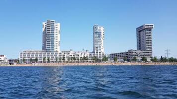 Paisagem costeira urbana com edifícios modernos altos, uma praia e vista para o mar.