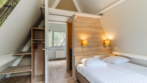 Quarto com cama, duas luminárias fixadas na parede, cabeceira de madeira e escada que leva a uma área externa.