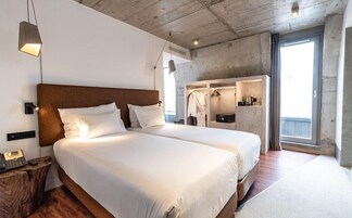 Quarto de hotel moderno com uma cama grande, closet espaçoso e vista para o exterior.