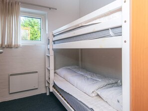 Quarto com beliche, janela, radiador e porta.