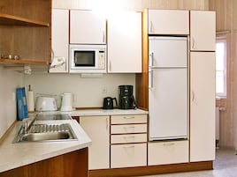 Cozinha compacta com micro-ondas, cafeteira e geladeira.