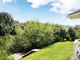 Uma área externa com gramado e uma escada de madeira que leva a uma construção branca.