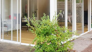 Uma casa moderna com porta de vidro, um pequeno jardim com pedras e um deck de madeira.