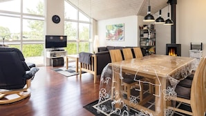 Uma sala de estar ampla com uma mesa de jantar de madeira, um sofá, uma televisão e uma lareira.