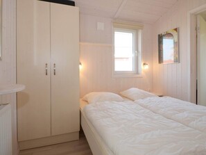 Quarto com cama, guarda-roupa, janela e luminária na parede.