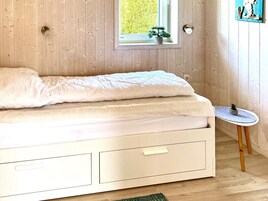 Quarto com cama, uma mesa pequena e janela com vista para o verde.