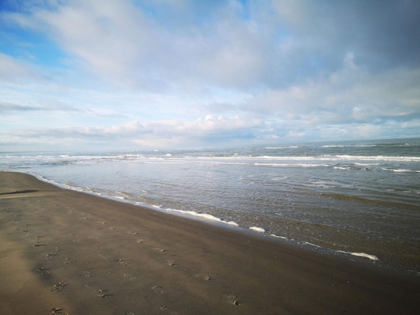 Uma praia com extensa faixa de areia e ondas suaves.