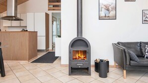 Uma sala de estar moderna com lareira, um sofá e uma área de cozinha com armários e chaminé.