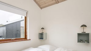 Quarto com uma cama de solteiro, uma janela e duas luminárias.