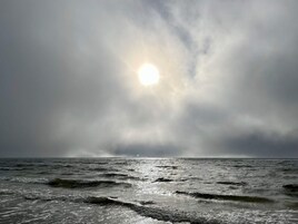 Céu nublado sobre o oceano, com raios de sol a espreitar.