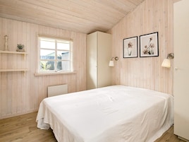 Quarto com cama, janela, guarda-roupa e luminárias fixadas na parede.