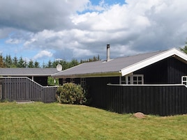 Um edifício de madeira escura com telhado inclinado, chaminé e antena parabólica.