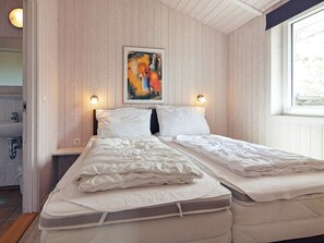 Quarto com duas camas, paredes de madeira, um quadro e uma janela.